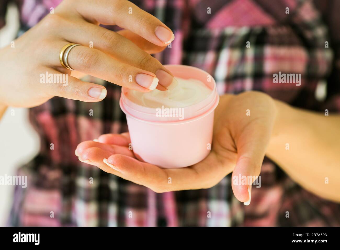 Female hands holding natural white smooth cream, touching it with ...