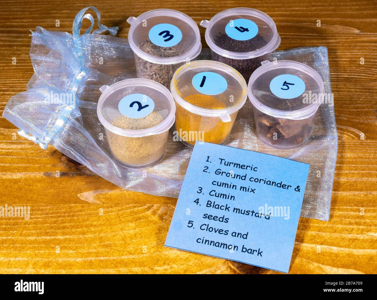 Five small plastic pots on a pretty bag, containing samples of Indian ...