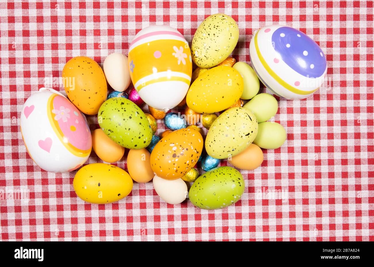 Mix of easter eggs of all colors and sizes on a background of red and ...