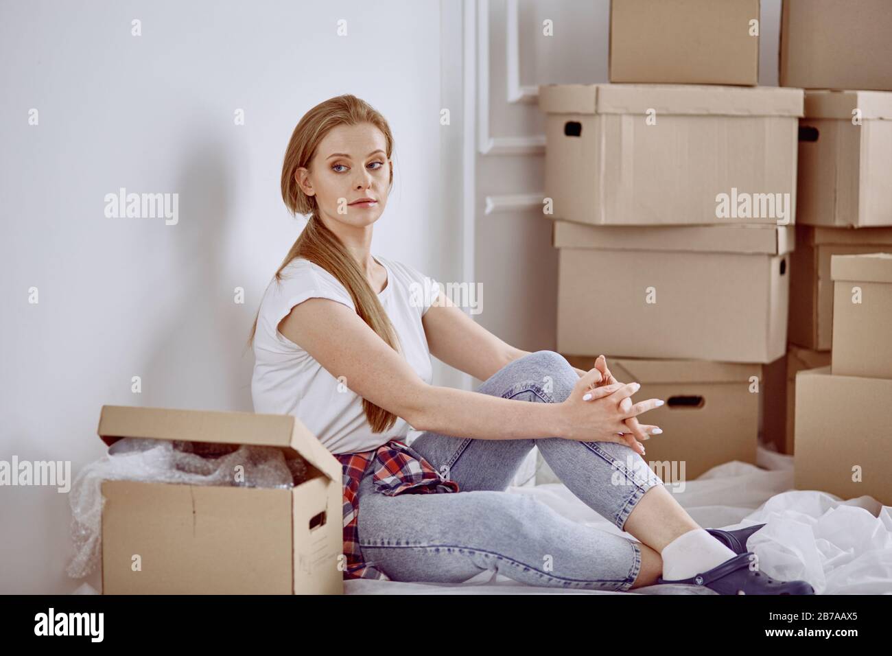 A beautiful single young woman unpacking boxes and moving into a new ...