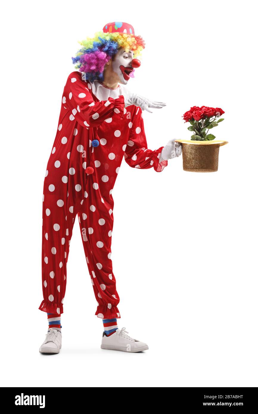 Full length shot of a clown holding a hat with red roses inside ...