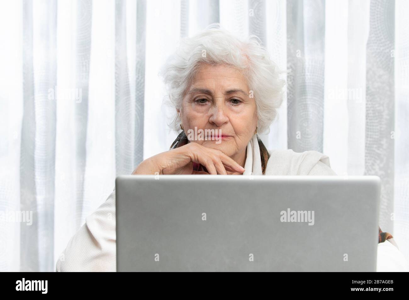 old lady looking at a computer on a wooden table. concept of technology ...