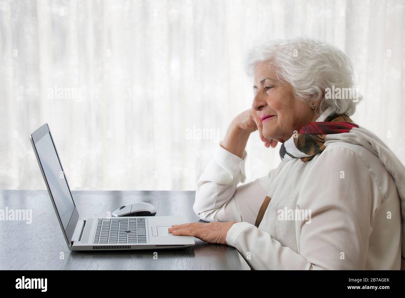 old lady looking at a computer on a wooden table. technology concept ...