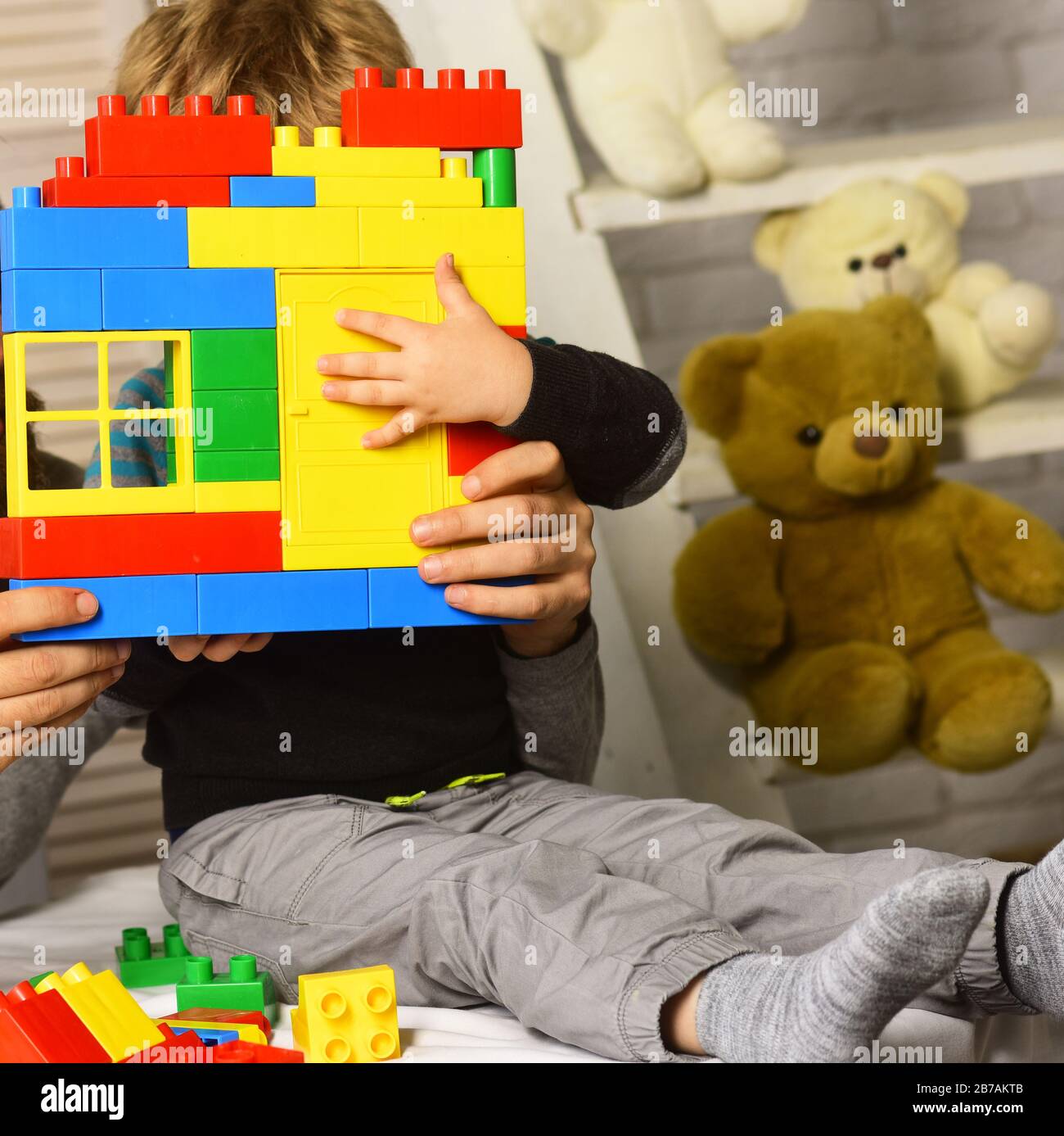 Family game and childhood concept. Kid hides behind building wall made ...