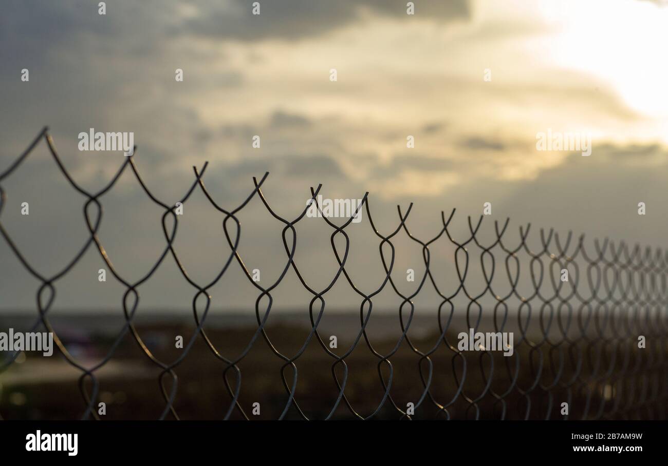 Restricted area concept. A metal mesh fence enclosing a restricted area ...
