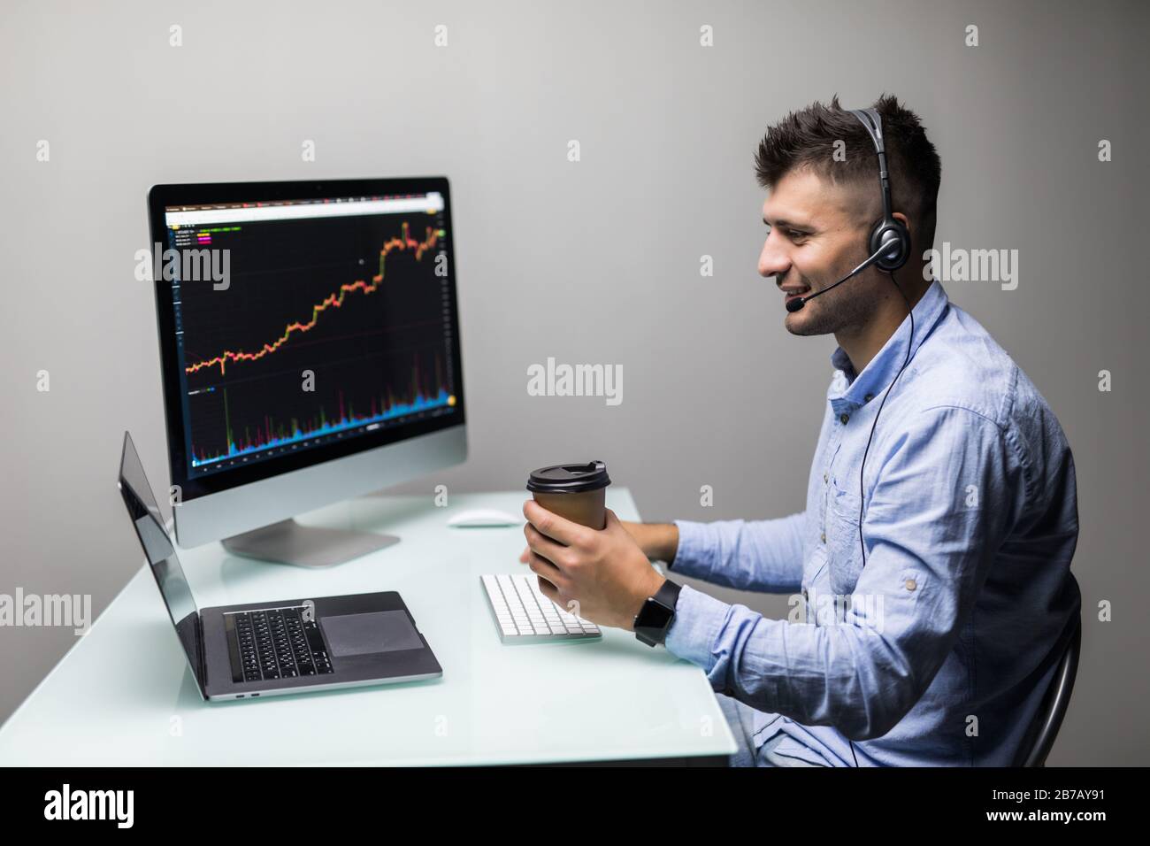 Side view of male trader using multiple computer screens while ...