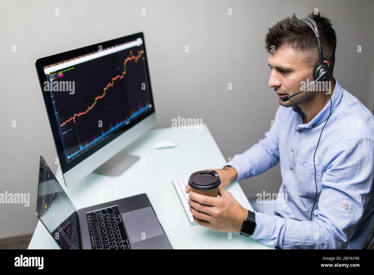 Side view of male trader using multiple computer screens while ...
