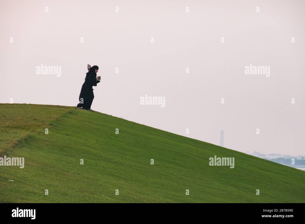A Muslim woman walks down a grassy hill in Doha, Qatar Stock Photo - Alamy