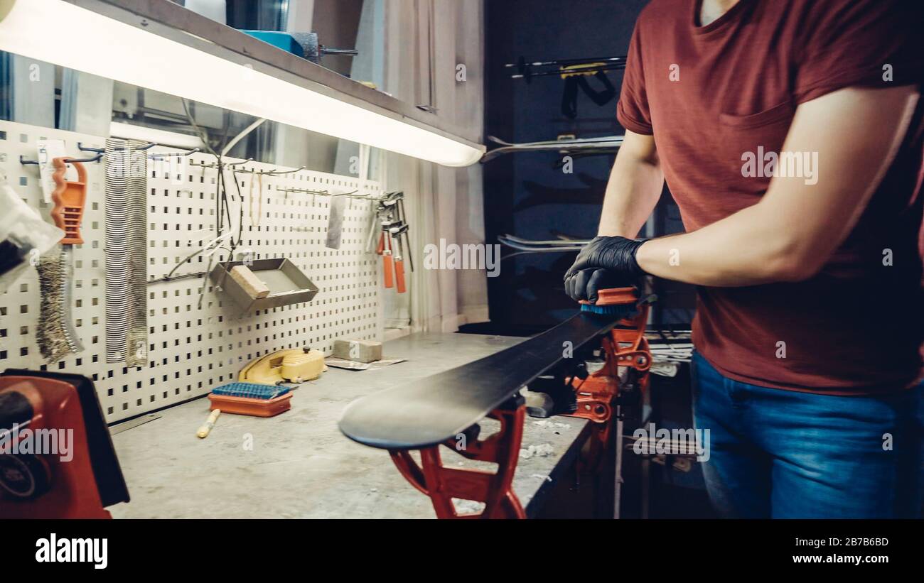 Cleaning ski base with fine hair brush. Attractive worker cleaning ski ...