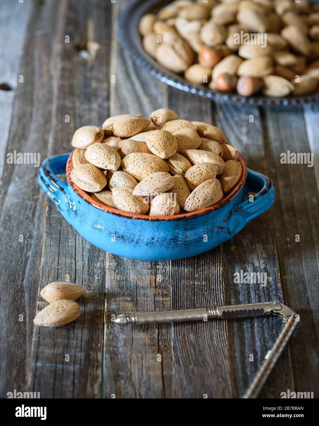 Almonds in a blue bowl on wooden table. Nut cracker tool. Health ...