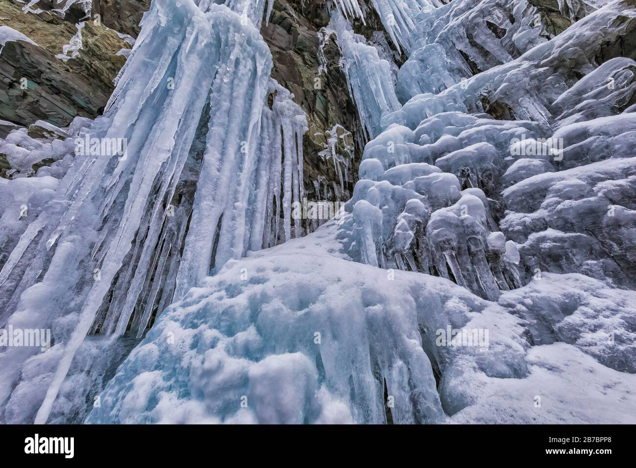 Frozen seeps forming icicles and waterfalls along the rocky cliffs of ...