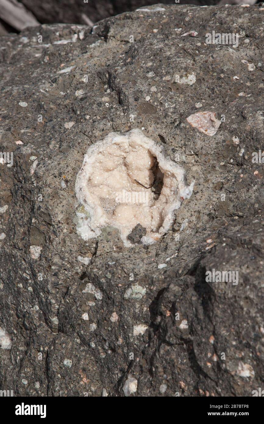 A circular depression on a boulder filled with white angular crystals ...