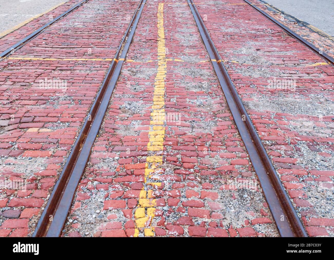 An old, worn red brick road showing trolley tracks that are no longer ...