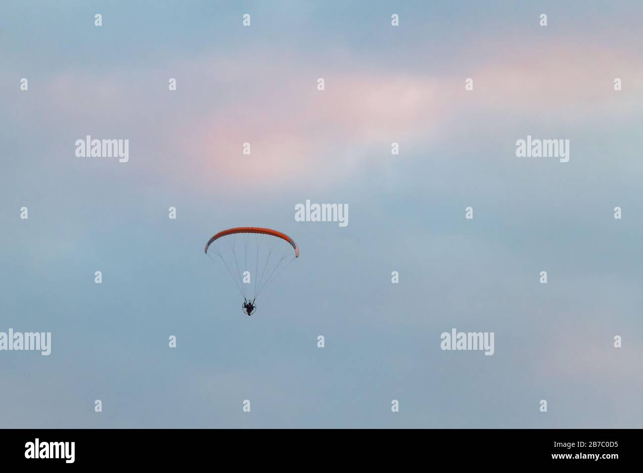 Powered paragliding, man flying high in a sky with parachute and engine ...