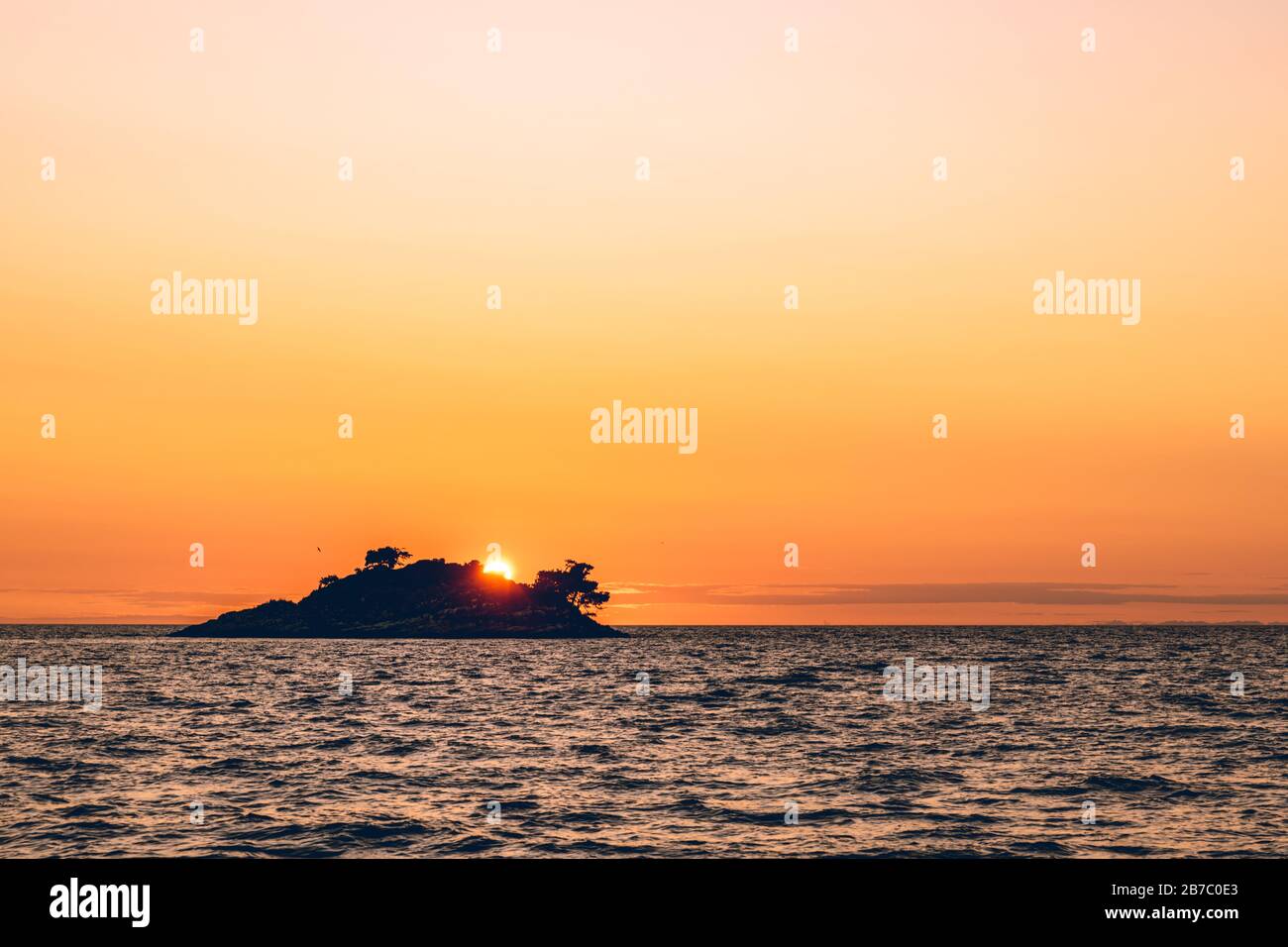 Romantic view of sunset over a deserted island in the distance at sea ...