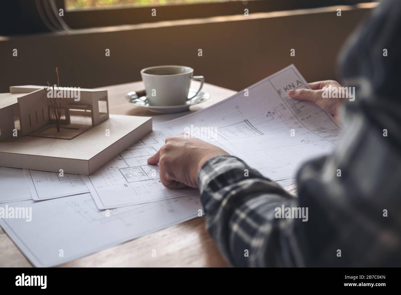 An architect working on an architecture model with shop drawing paper ...