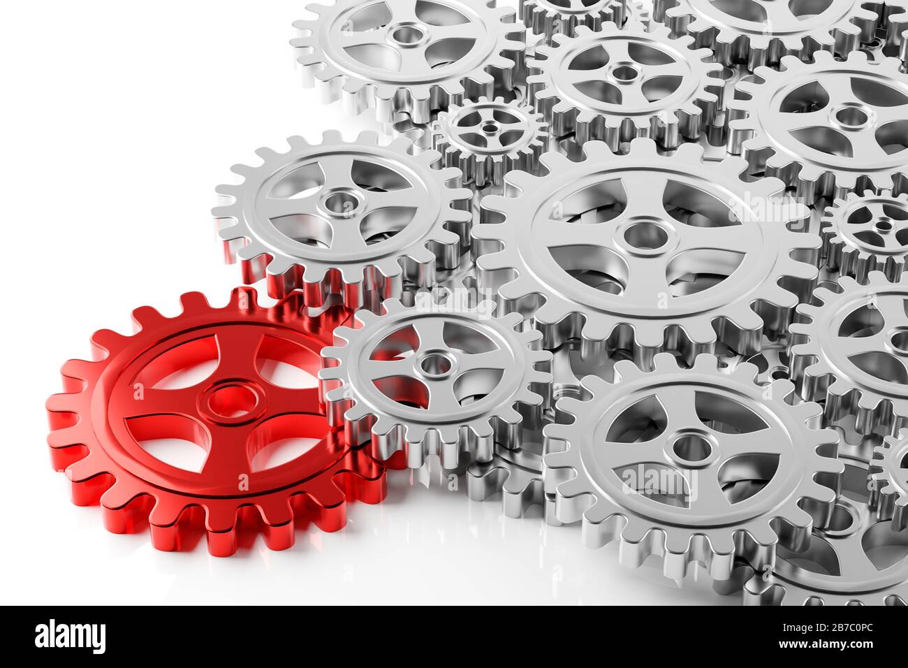 Heap of mechanical gear cogwheels wiith one red key cog over white ...