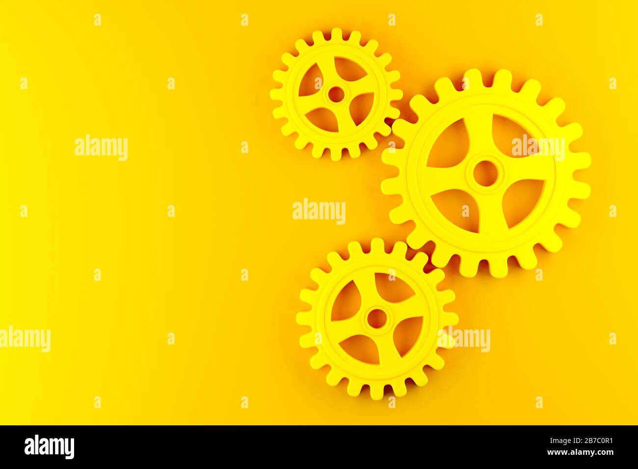 Three yellow mechanical gear cogwheels over yellow background ...