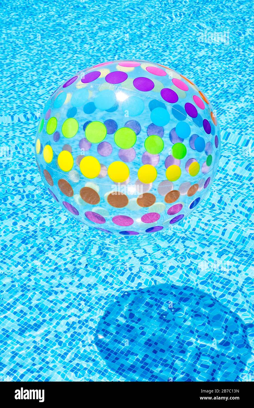 Inflatable colourful ball floating in blue swimming pool water ...