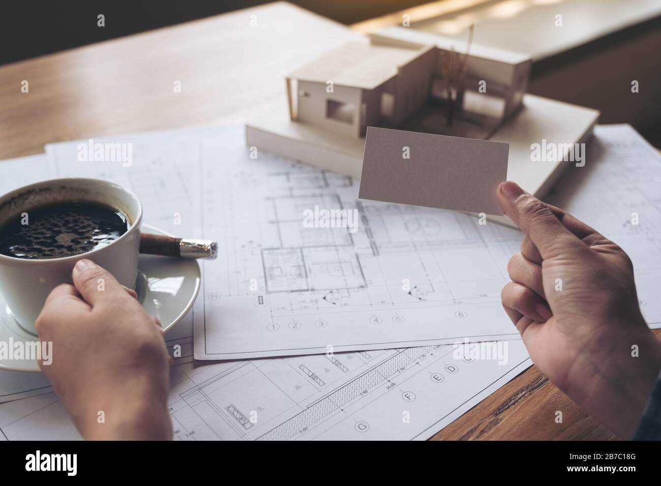 A hand holding and showing an empty business card with an architecture ...