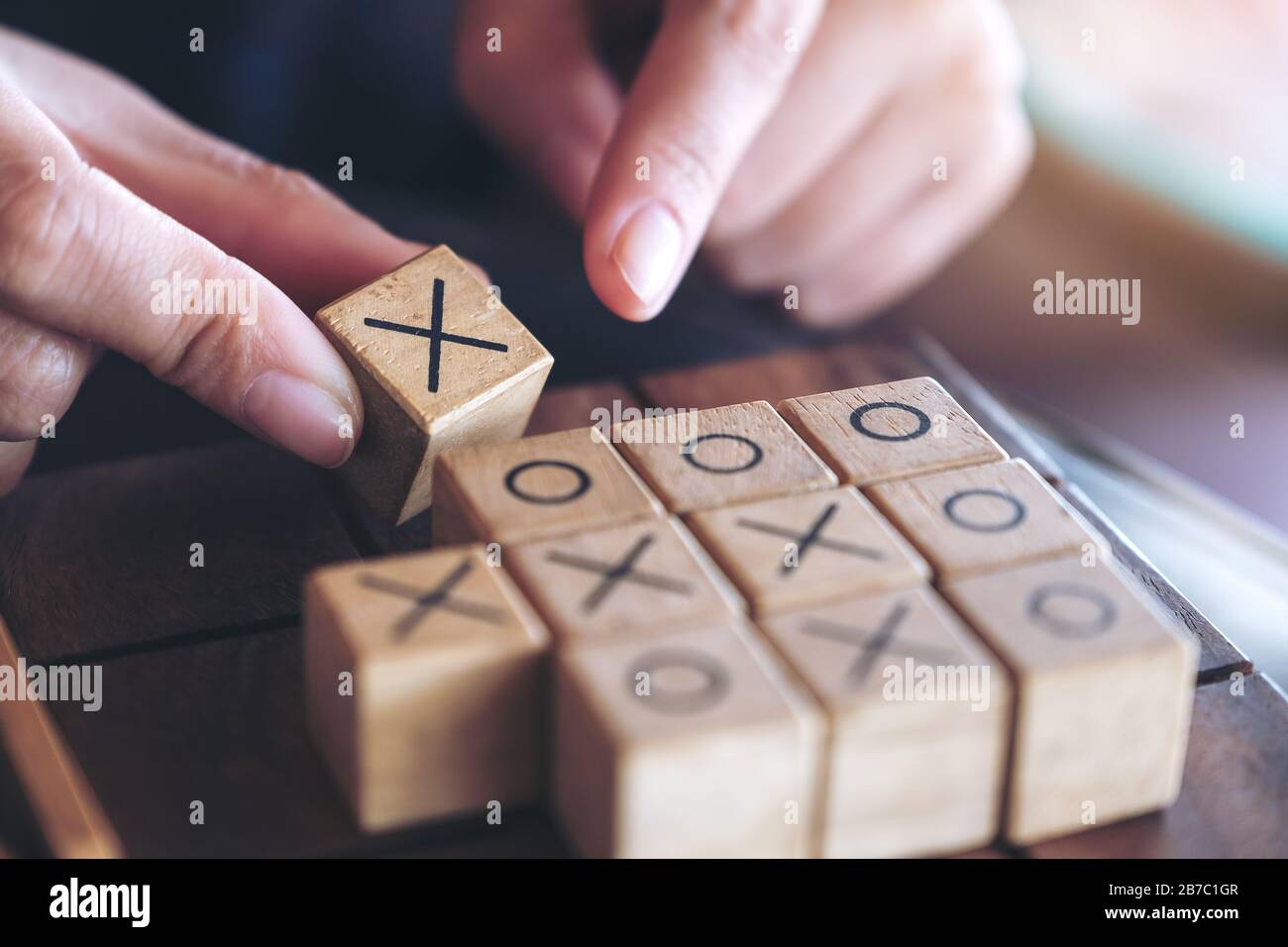 Closeup image of people playing wooden Tic Tac Toe game or OX game ...