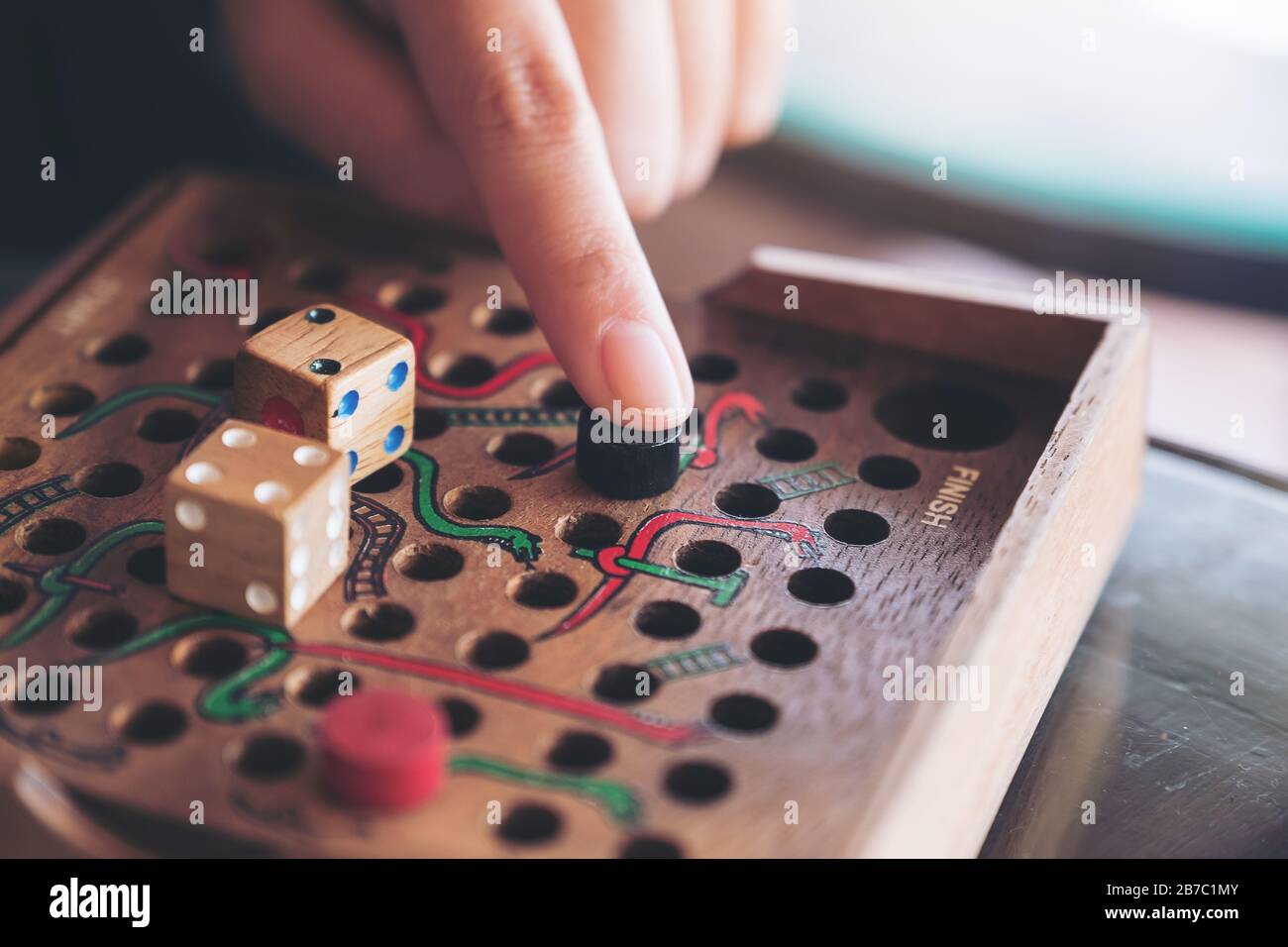 Closeup image of a hand playing wooden Snakes and Ladders game Stock ...