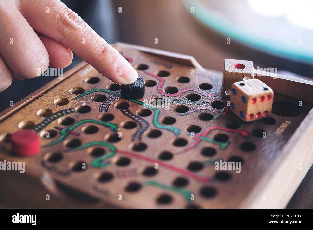 Closeup image of a hand playing wooden Snakes and Ladders game Stock ...