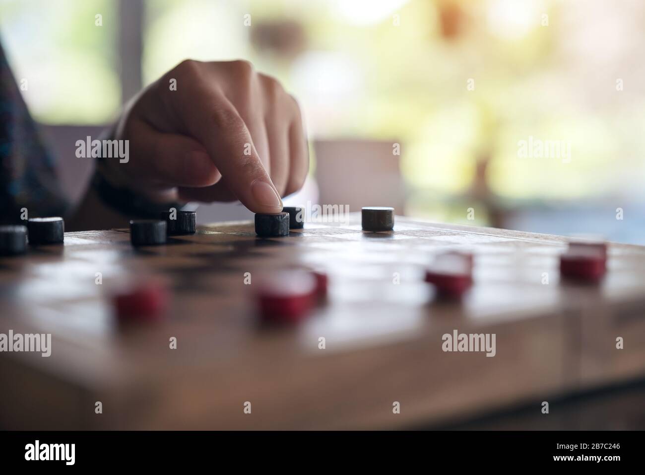 Closeup image of people playing and moving checkers in a chessboard ...