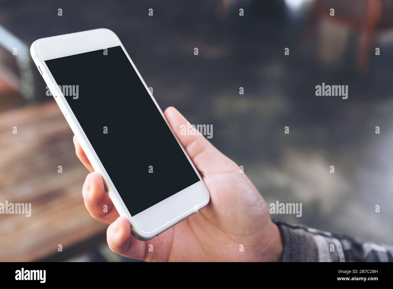 Mockup image of hand holding white mobile phone with blank black screen ...