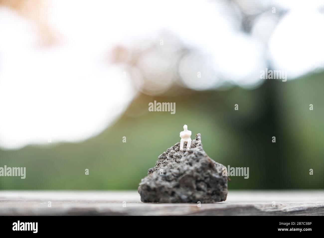 Closeup image of miniature figure model of a lonely man sitting on the ...