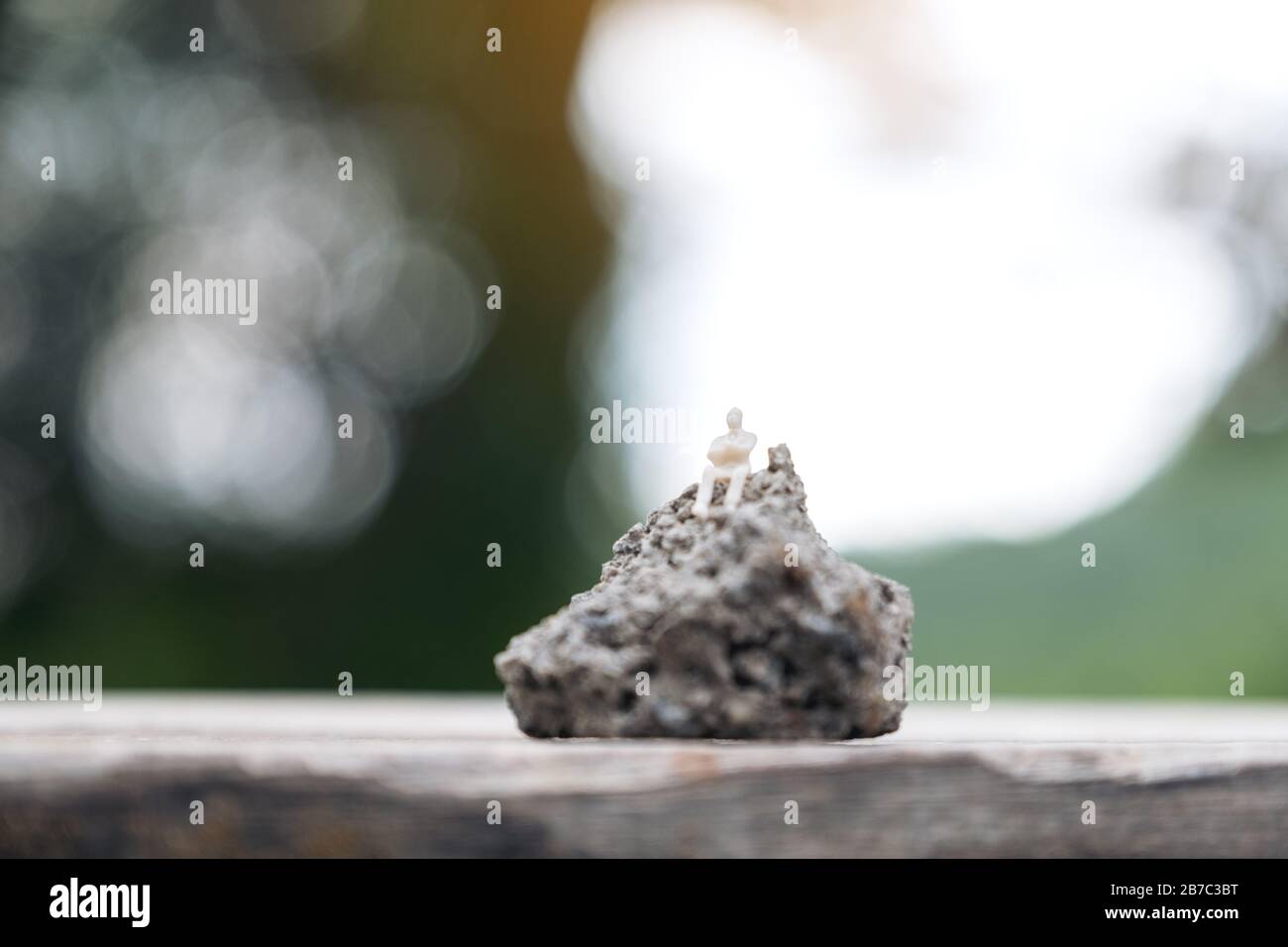 Closeup image of miniature figure model of a lonely man sitting on the ...
