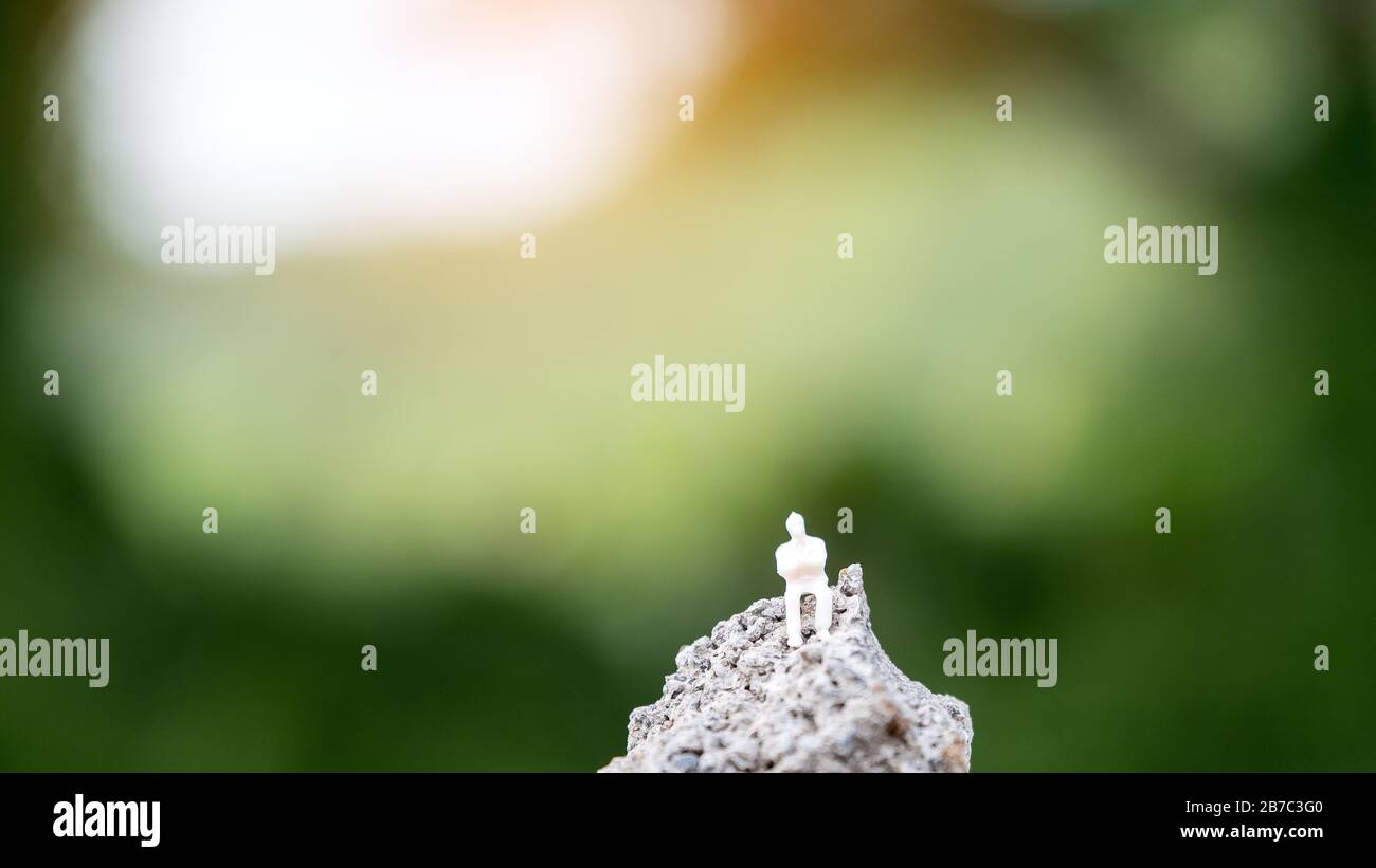 Closeup image of miniature figure model of a lonely man sitting on the ...