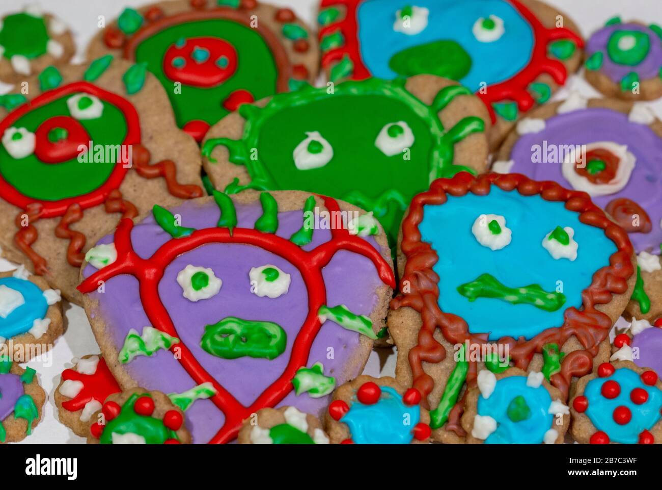 Cookies frosted with red, green, purple and blue, decorated like germs ...