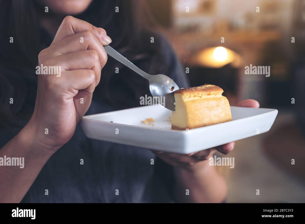 Closeup image of a woman holding and cheese cake with spoon to eat in ...