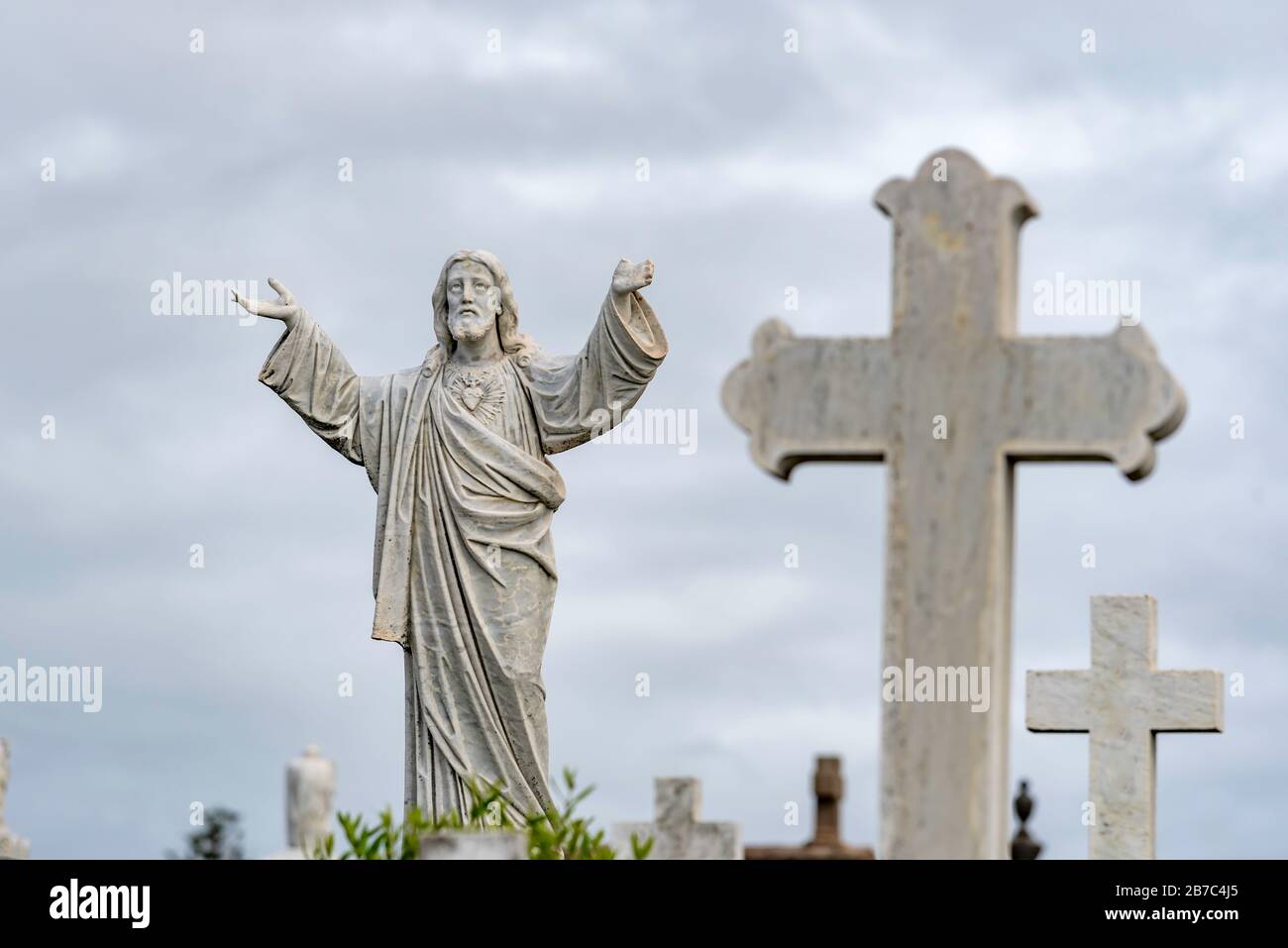 Marble crucifixes and a life-size Jesus figurine in a graveyard provide ...