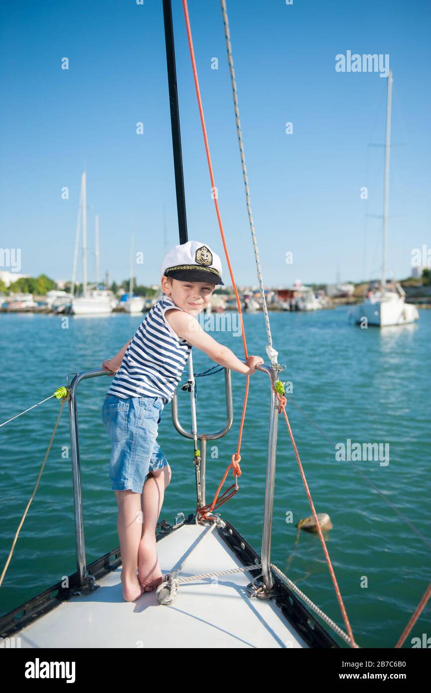 happy cute little boy in captain white hat striped tank top and denim ...