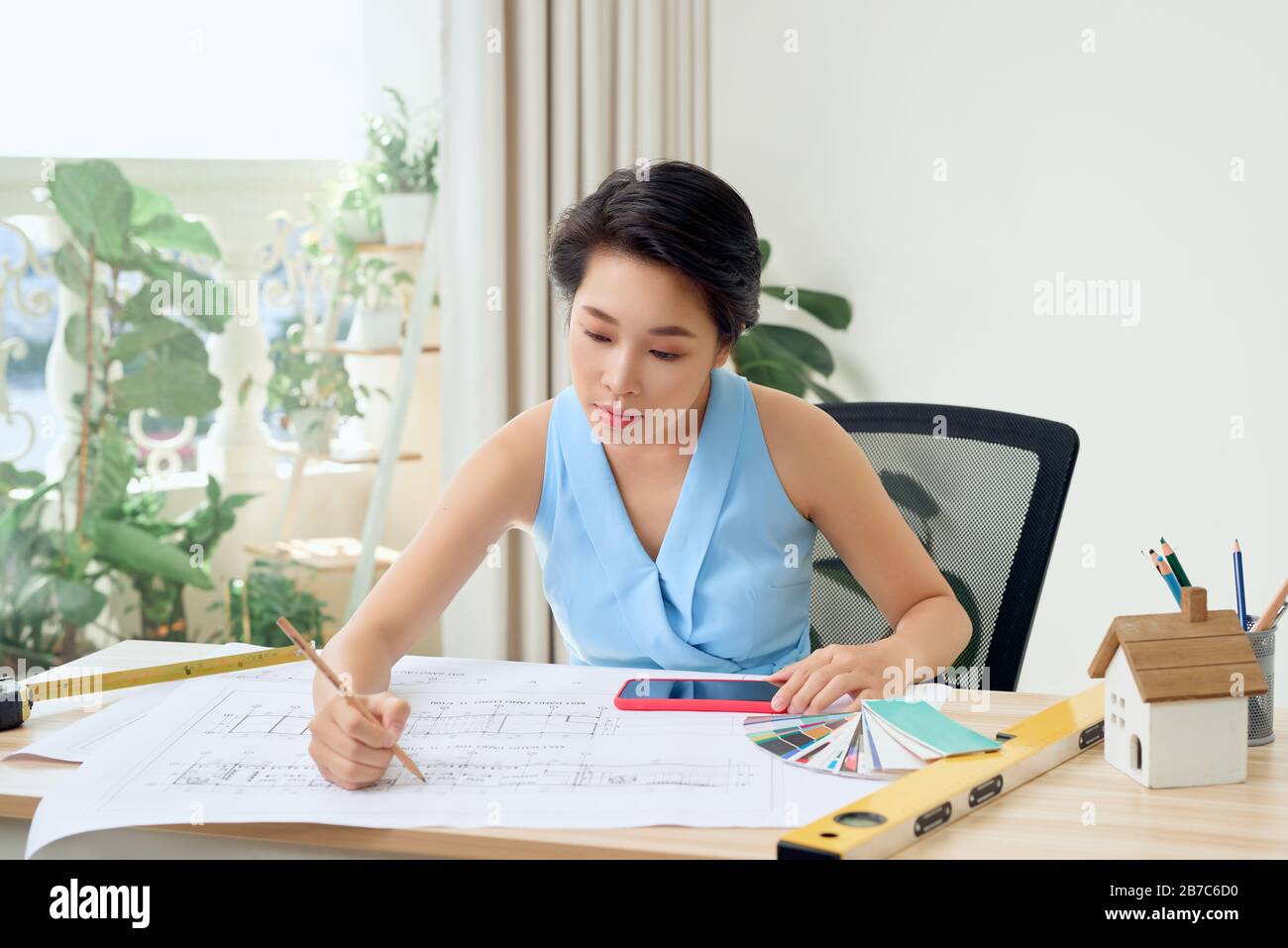 Asian female architect studying plans in office Stock Photo - Alamy