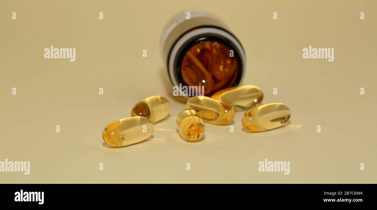 Yellow capsules tablet next to open pharmaceutical bottle close up ...