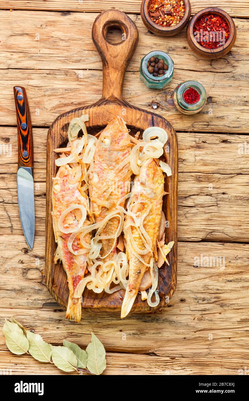 Mullet fish fried with horseradish rootsSpicy fry fish on cutting board ...