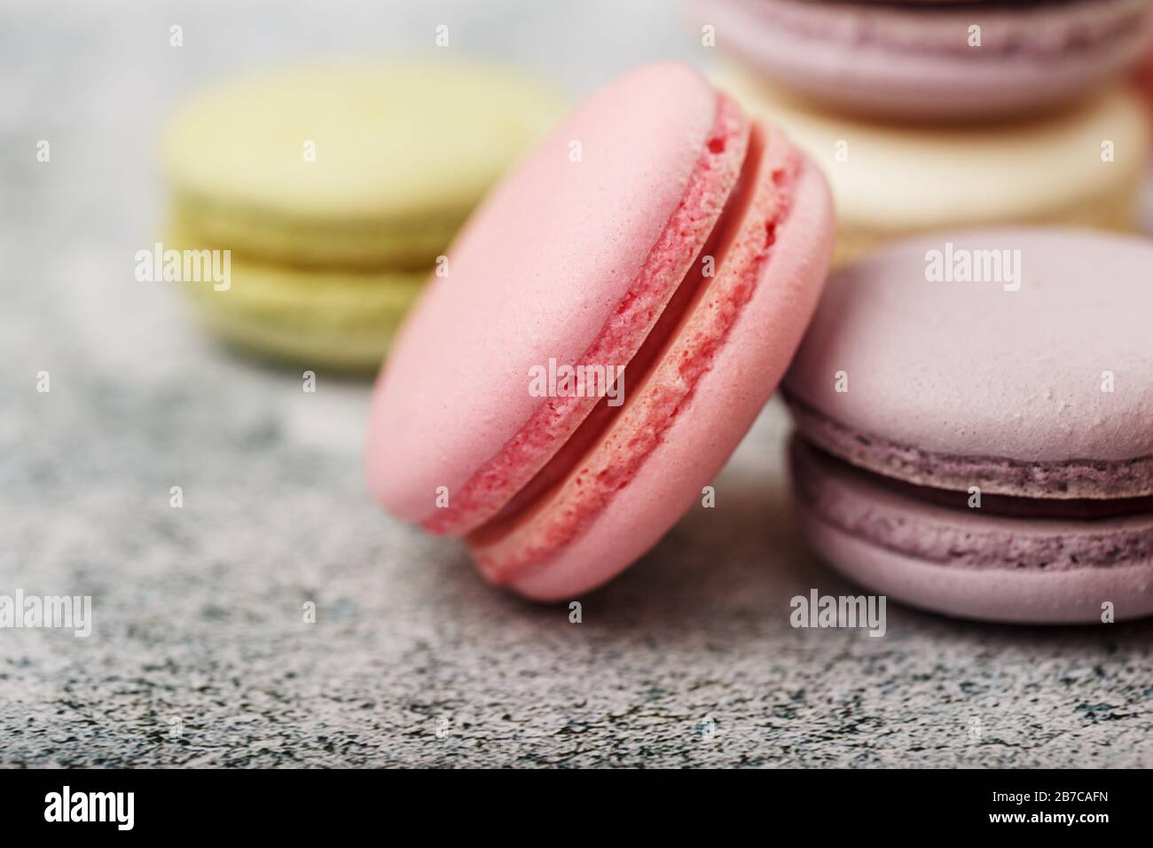 French macaroni cookies of different colors are on the gray table ...