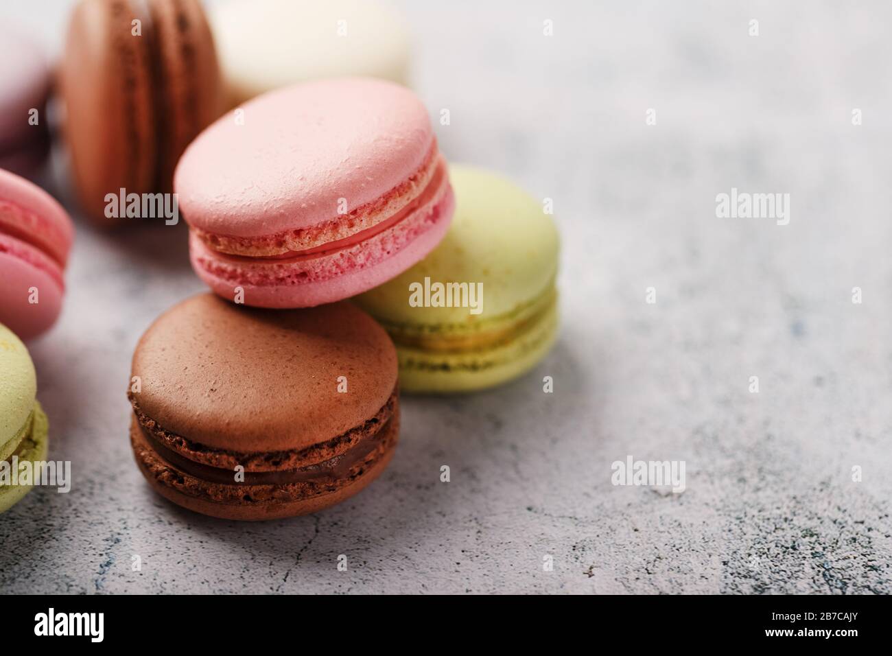 French macaroni cookies of different colors are on the gray table ...