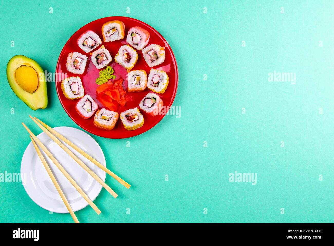 Red plate with sushi, filled with rolls of different kinds, next to ...
