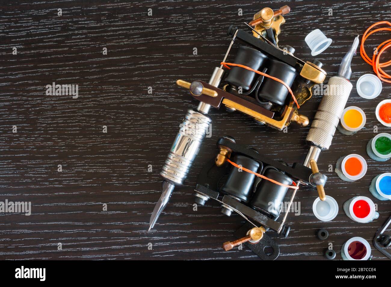 Two tattoo machines and ink on a black background with space for text ...