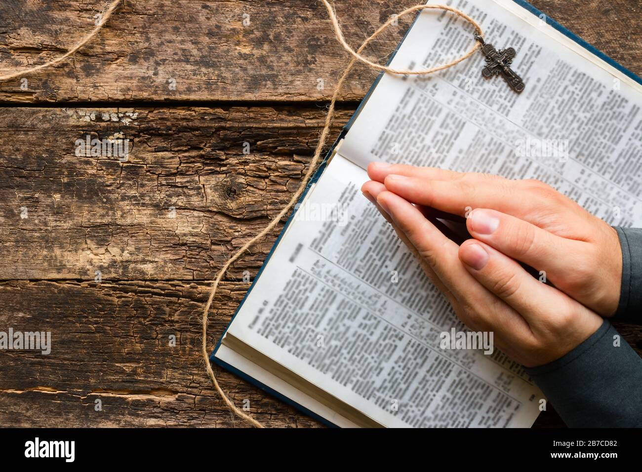 man reads a prayer from the Bible on the wooden background with space ...