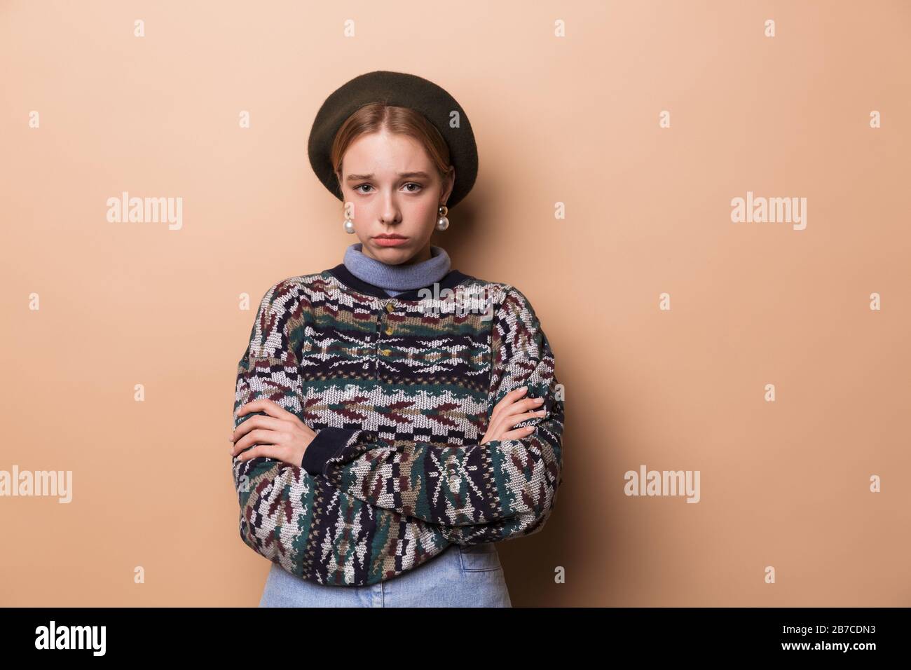 Serious concentrated lady in cap looking camera and holding nhands ...