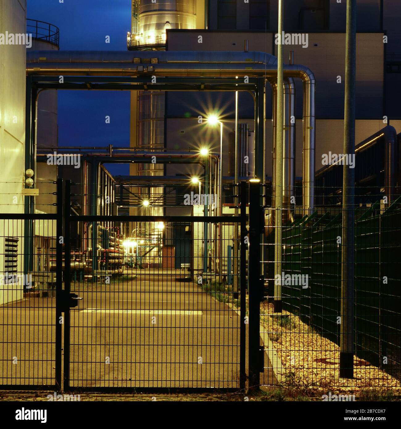 Line of lit lamp posts on an alley behind a locked gate Stock Photo - Alamy