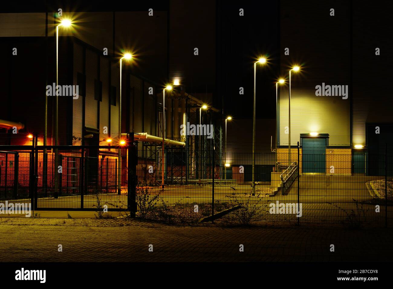 Image of a well lit gated lot behind buildings at night Stock Photo - Alamy