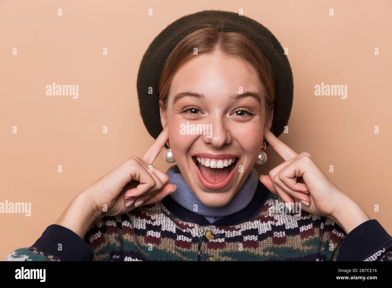 Photo of pretty excited woman in earrings plugging her ears and ...