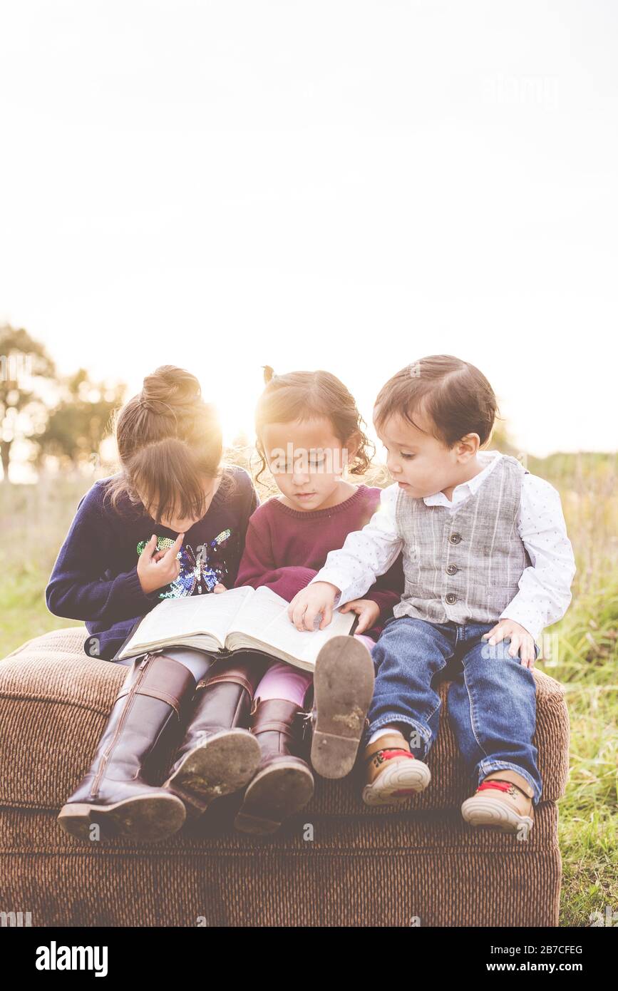 Little kids looking through the Bible in a park during daytime Stock ...