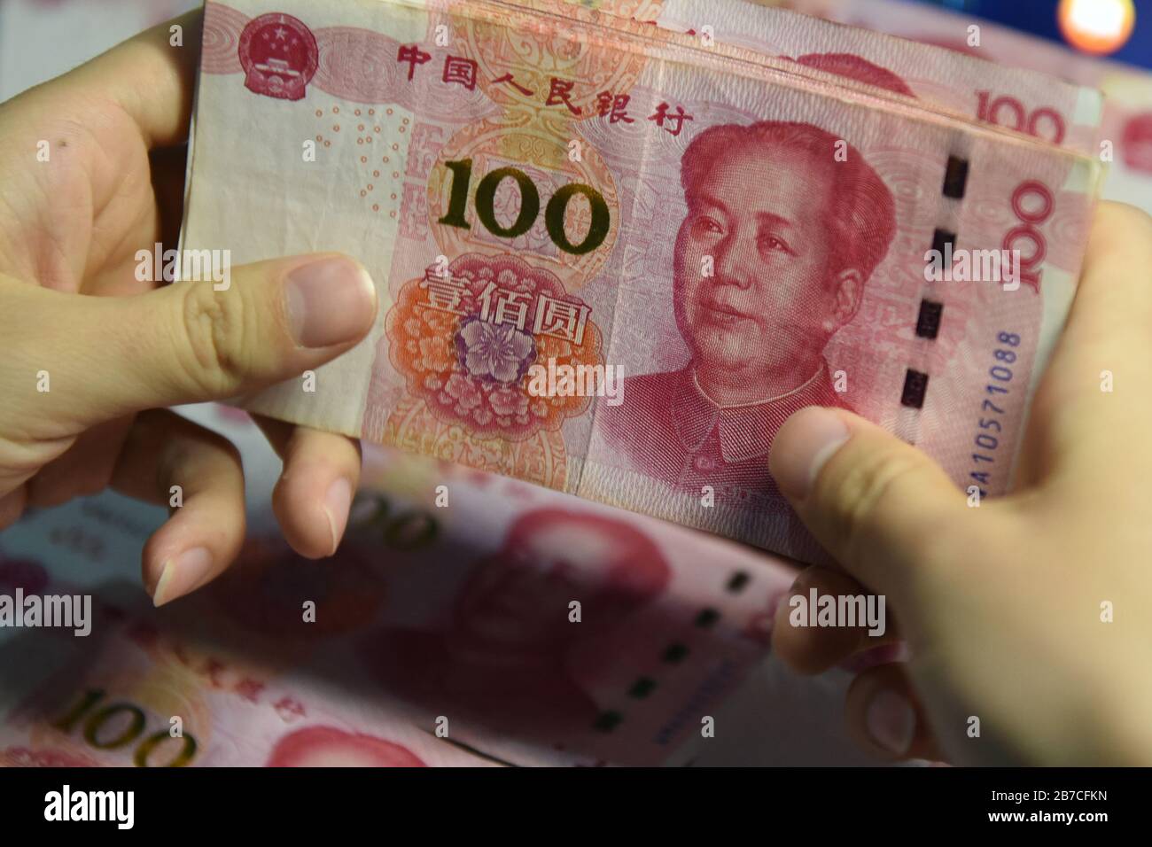 In this photo illustration a man holds 100 RMB notes Stock Photo - Alamy